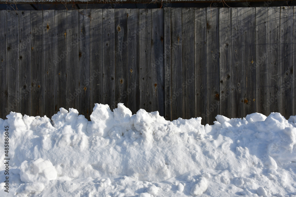 Winter background. A snowdrift on the background of an old fence made ...