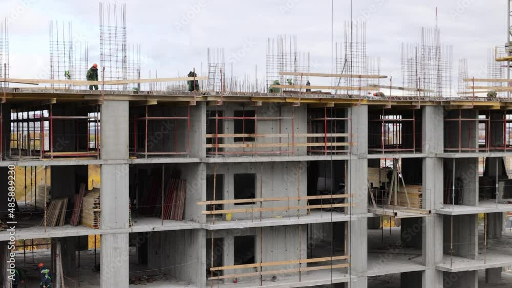Workers build a high-rise building of reinforced concrete, pouring ...
