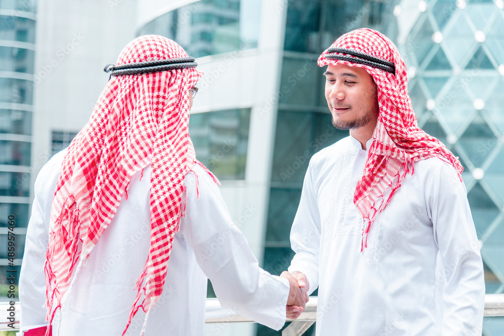 Arab Businessman Muslim dress shaking hands together in modern city UAE ...