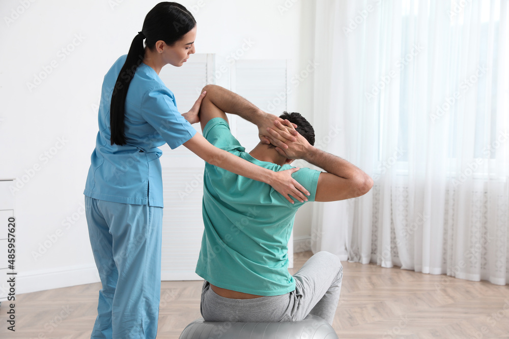 Orthopedist helping patient to do exercise in clinic. Scoliosis ...
