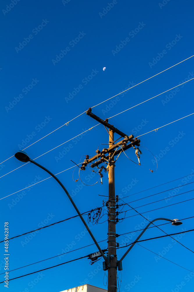 Many wires attached to the electric pole, the chaos of cables and wires ...