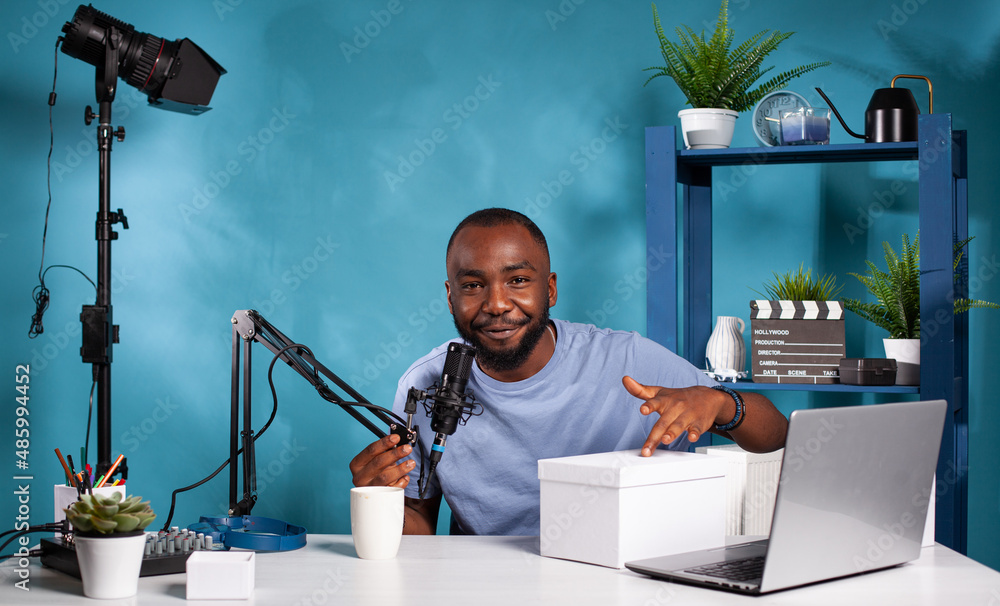 Vlogger holding boom arm microphone presenting giveaway product box in ...
