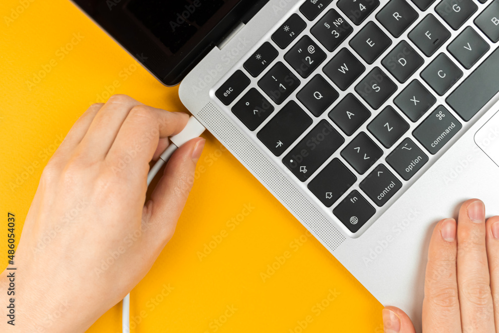 Woman plugging charger in a laptop. Type C charging port. Low battery ...