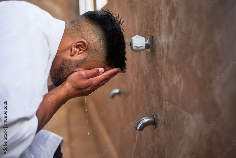 A young Muslim man performs wudu during prayers at a mosque by ...