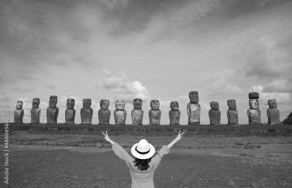 Monochrome image of a happy female visitor in front of the huge Moai ...