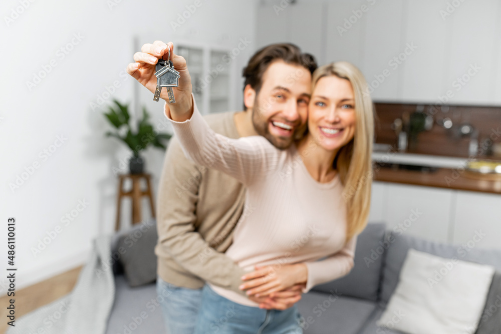 Young caucasian married couple homeowners smiling, showing keys from a ...