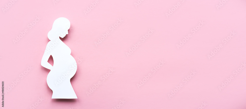 Paper silhouette of a pregnant woman casts a shadow on a pink ...