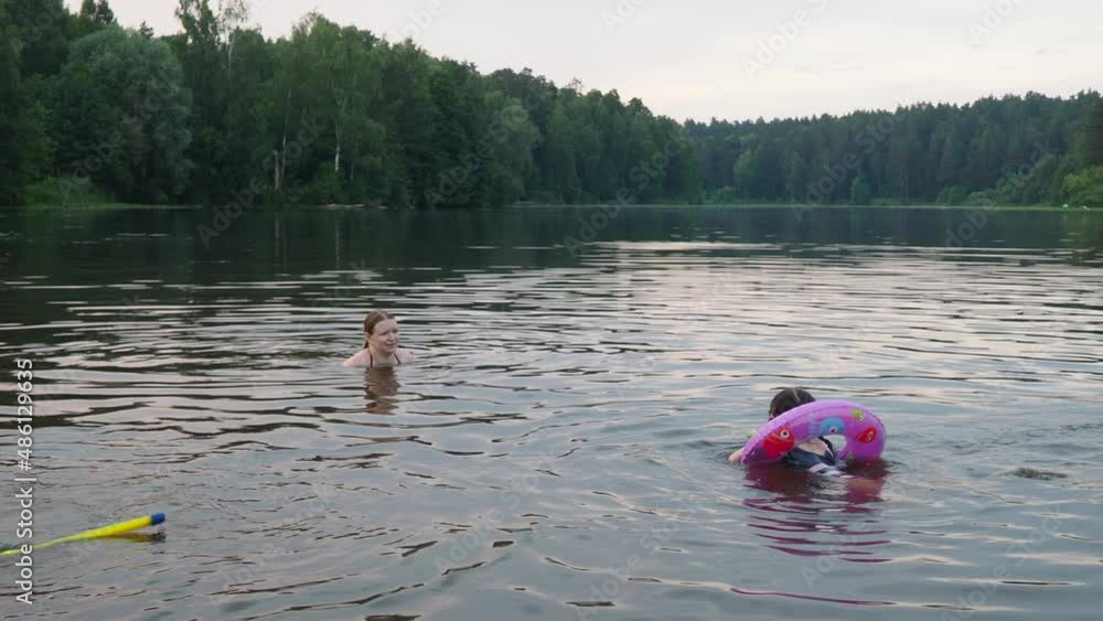 happy children, boy and girl swim in a forest lake. splashing each ...