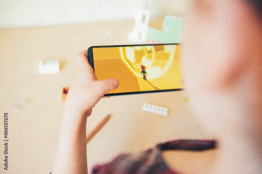 Little girl playing mobile games on her phone. Stock Photo | Adobe Stock