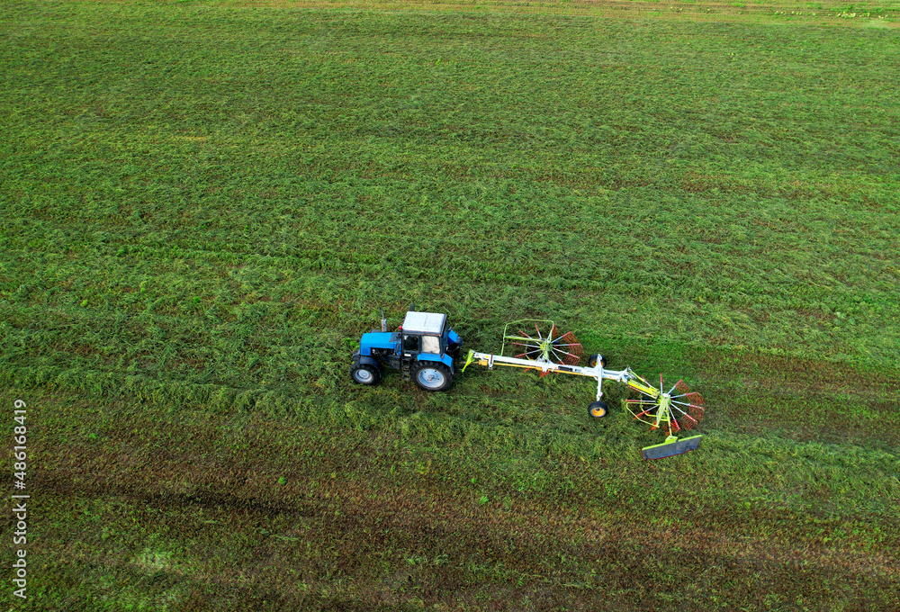 Tractor raking grass for silage harvesting. Agriculture farm machinery ...