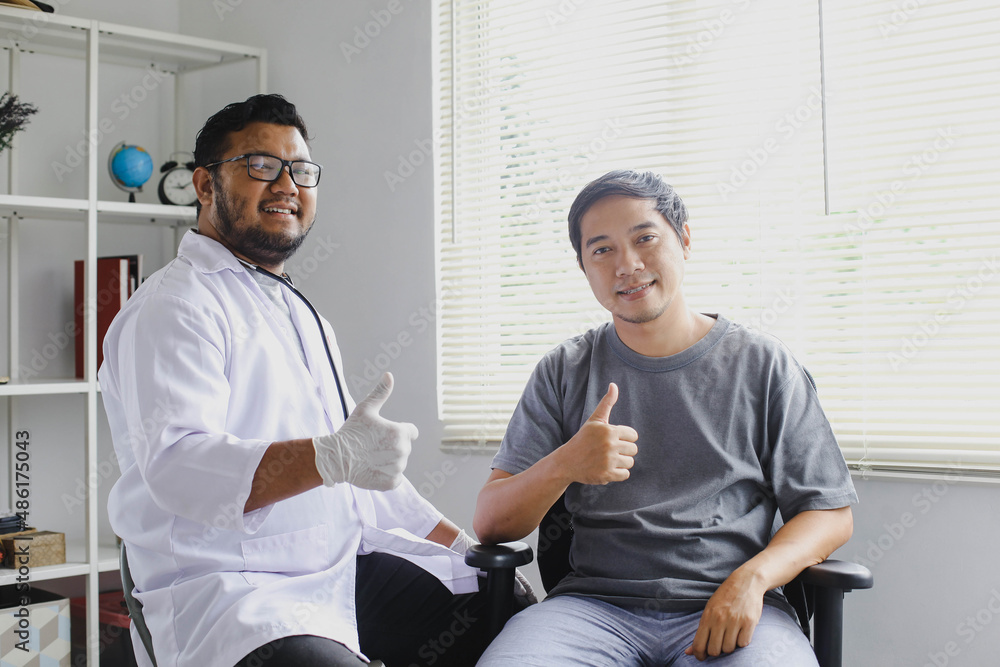 Smiling doctor and patient sitting side by side with thumbs up gesture ...