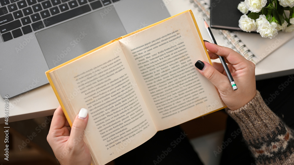 Female reading a novel book at her home office. Stock Photo | Adobe Stock