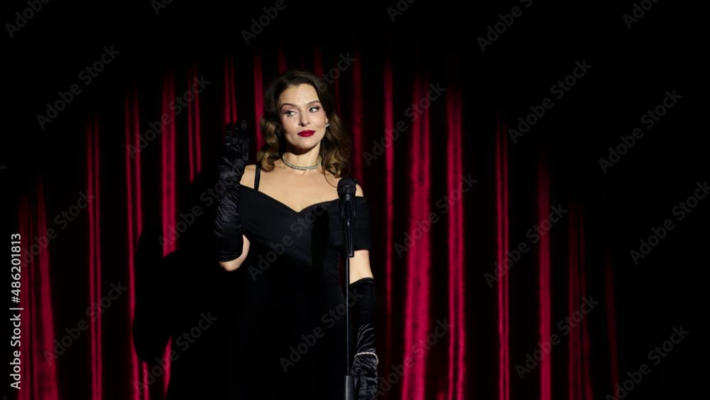 A young singer in a shiny black dress emotionally performs a song on ...