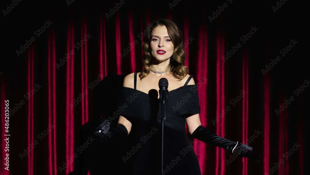 A young singer in a shiny black dress emotionally performs a song on ...