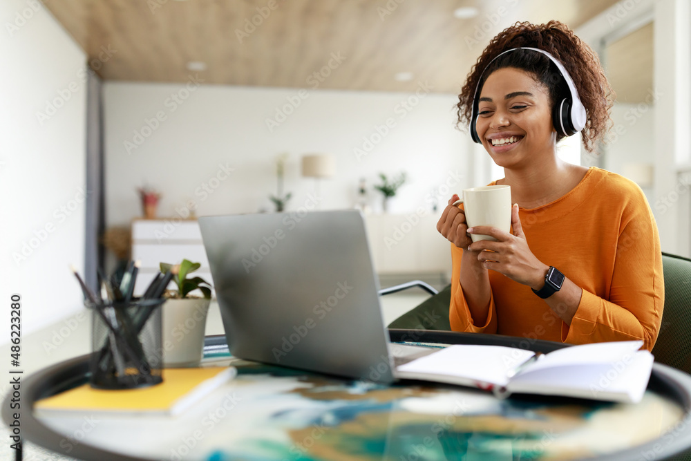Smiling black woman watching video on computer, drinking coffee Stock ...