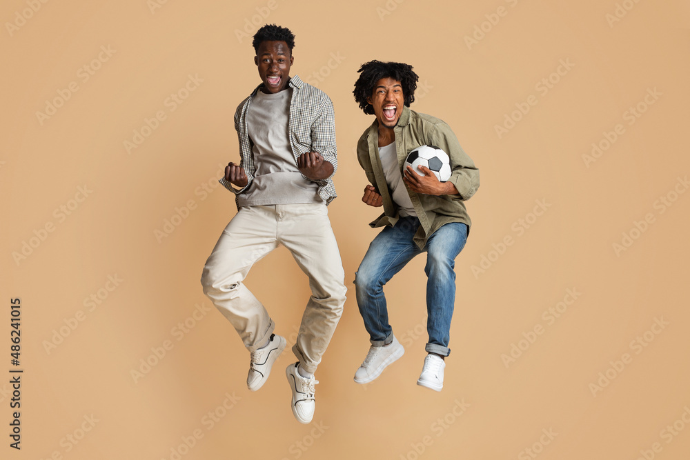 Football Fans. Two Euphoric Black Guys Jumping In Air With Soccer Ball ...