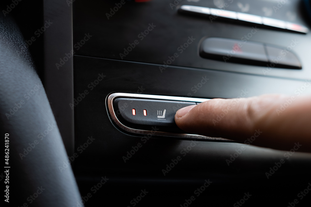 Finger pressing the button for heated seats in the car. Car equipment ...