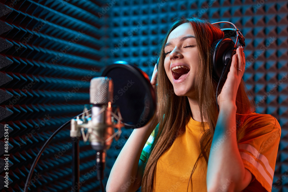 Teen girl in recording studio with mic over acoustic absorber panel ...