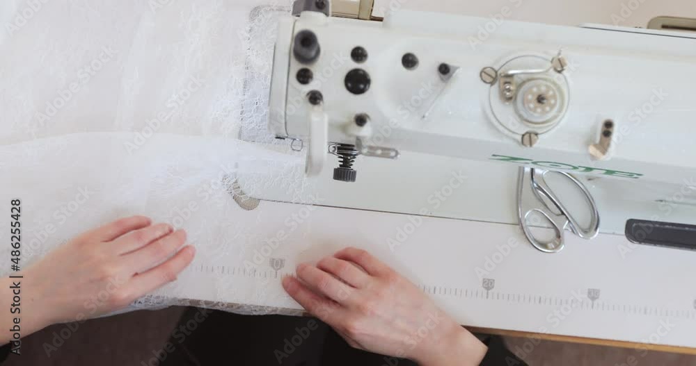 a seamstress on a sewing machine sews a transparent fabric. production ...
