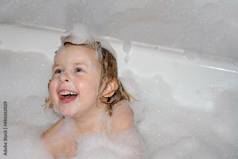 Kid having fun in the bath with bubbles. Happy child enjoying bath time ...
