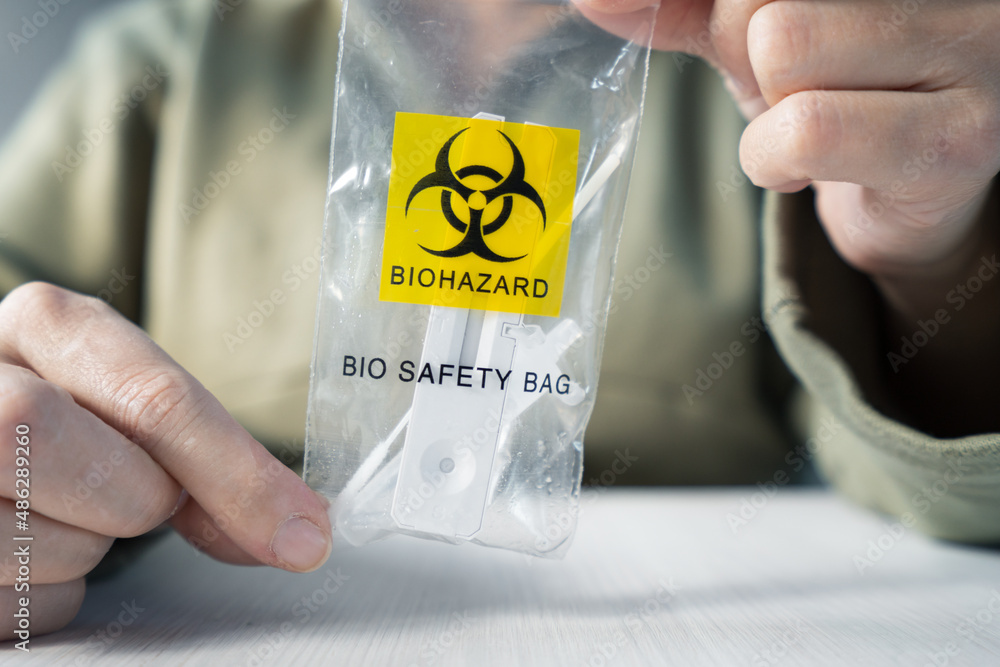 Person are holding biohazard bio safety bag with used antigen test car ...