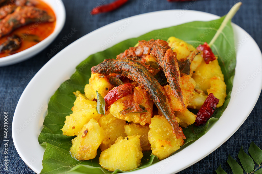 tapioca and spicy hot Kerala fish curry Indian food on banana leaf ...