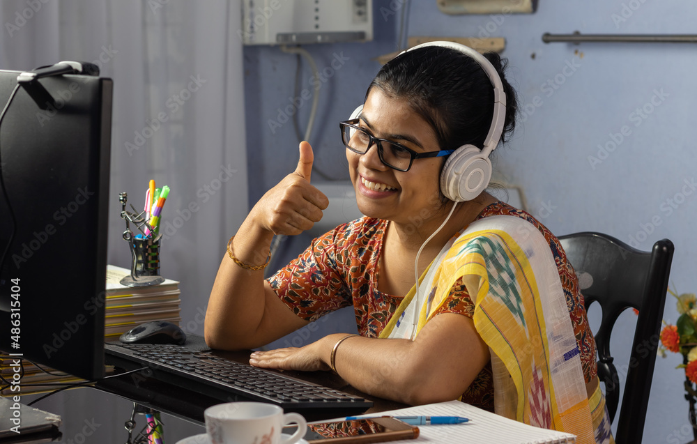 Indian woman in saree working on computer and talking over internet ...