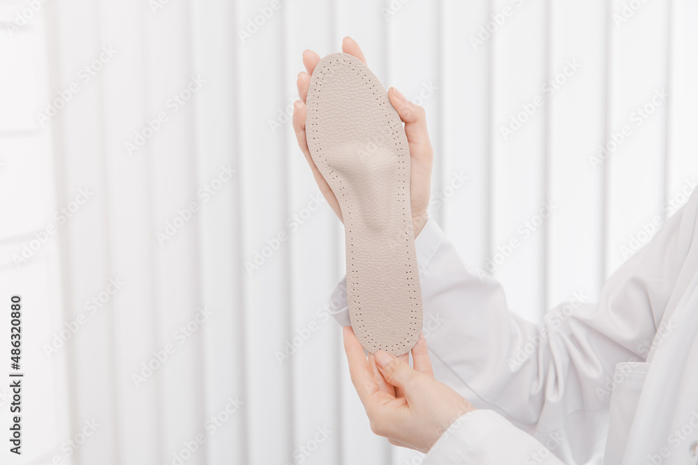 Doctor holding orthopedic insoles in his hands. Orthopedist tests the ...