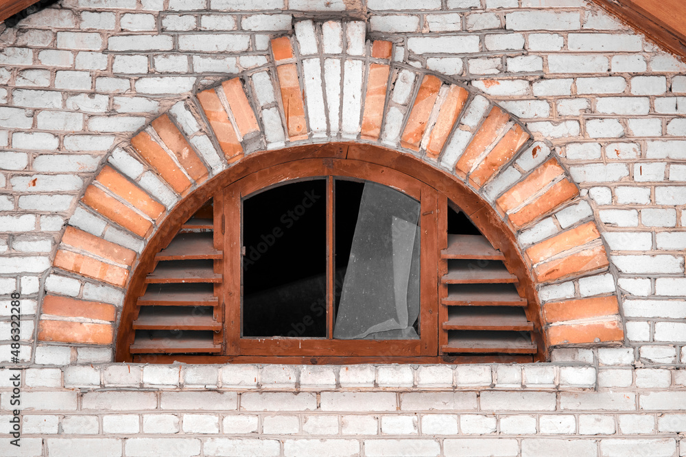 Old arched window of white and orange bricks with broken glass in ...