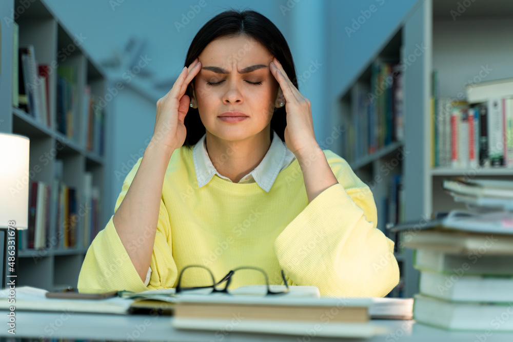 Anxious young woman with hands at her neck feeling tired while studying ...