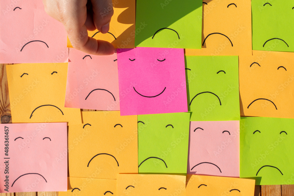 mano de mujer colocando un posit con una cara sonriente encima de ...
