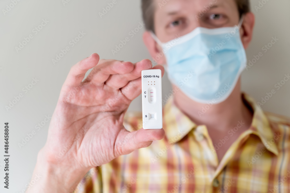 Man wearing face mask holding Covid-19 rapid antigen test cassette with ...