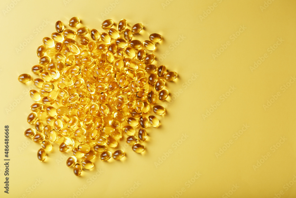 Pile of golden capsules of vitamin D3 on a yellow background with free ...