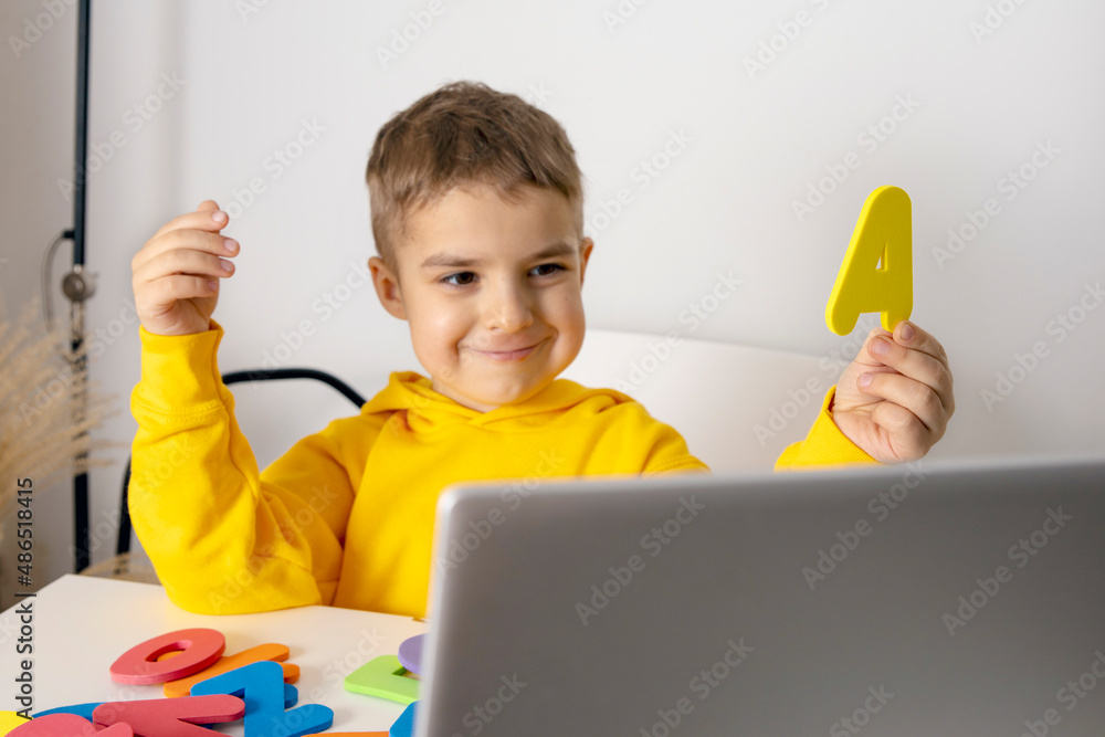 Adorable, cute, little boy learning alphabet online, with laptop at ...