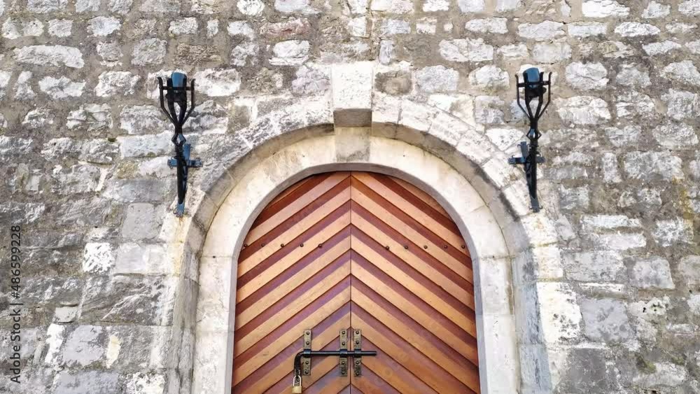 Arched heavy wooden door with fishbone pattern on the front wall of an ...