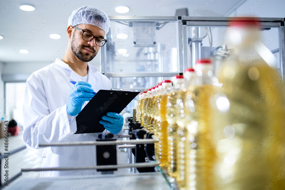 Food factory worker taking notes and controlling production line of ...