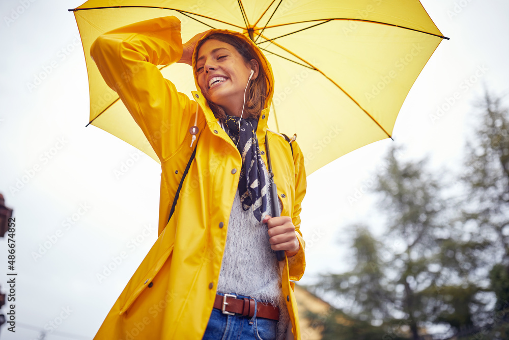 Shot from below of a young cheerful woman with a yellow raincoat and ...