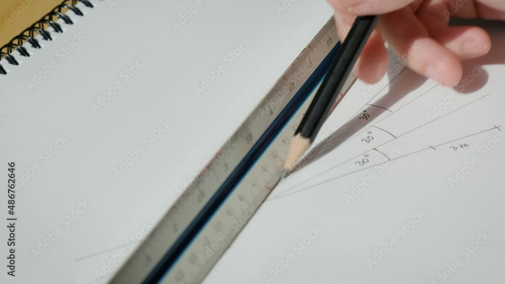 Hand of a man using a wooden pencil to draw lines on paper with an ...