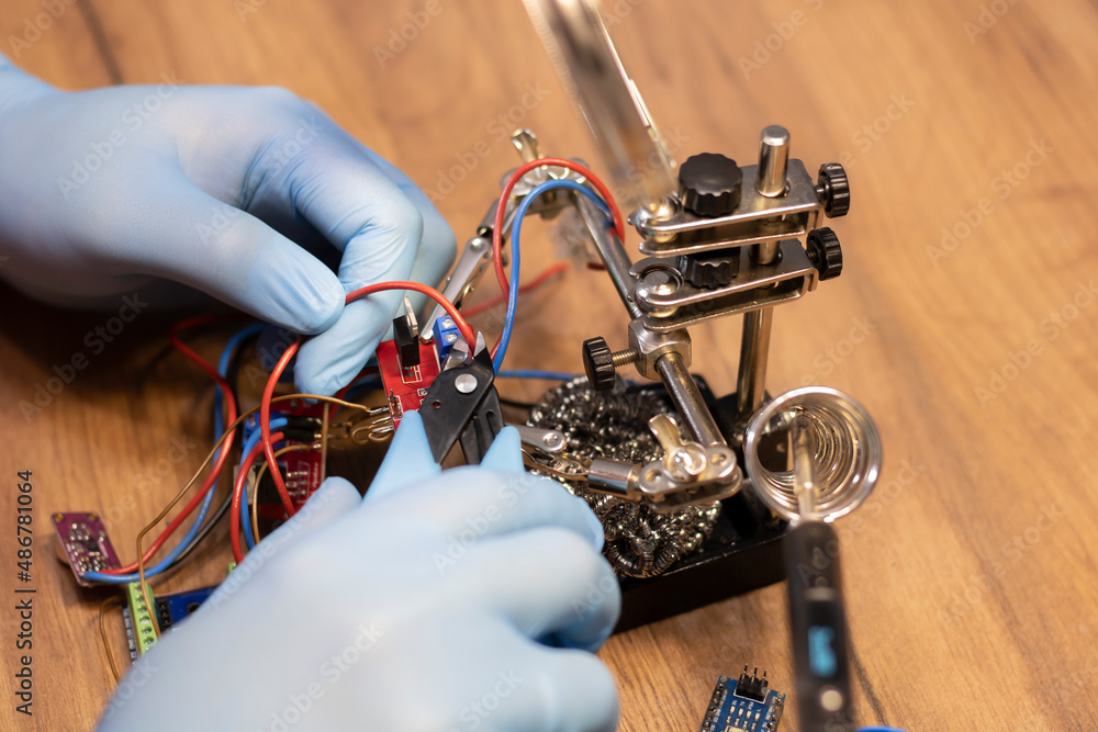 Hands hold side cutters and cut the wire, soldering the board with a ...