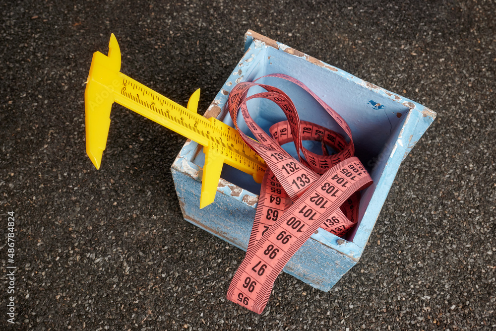 Centimeter tape and calipers inside a wooden box on ruberoid grain ...