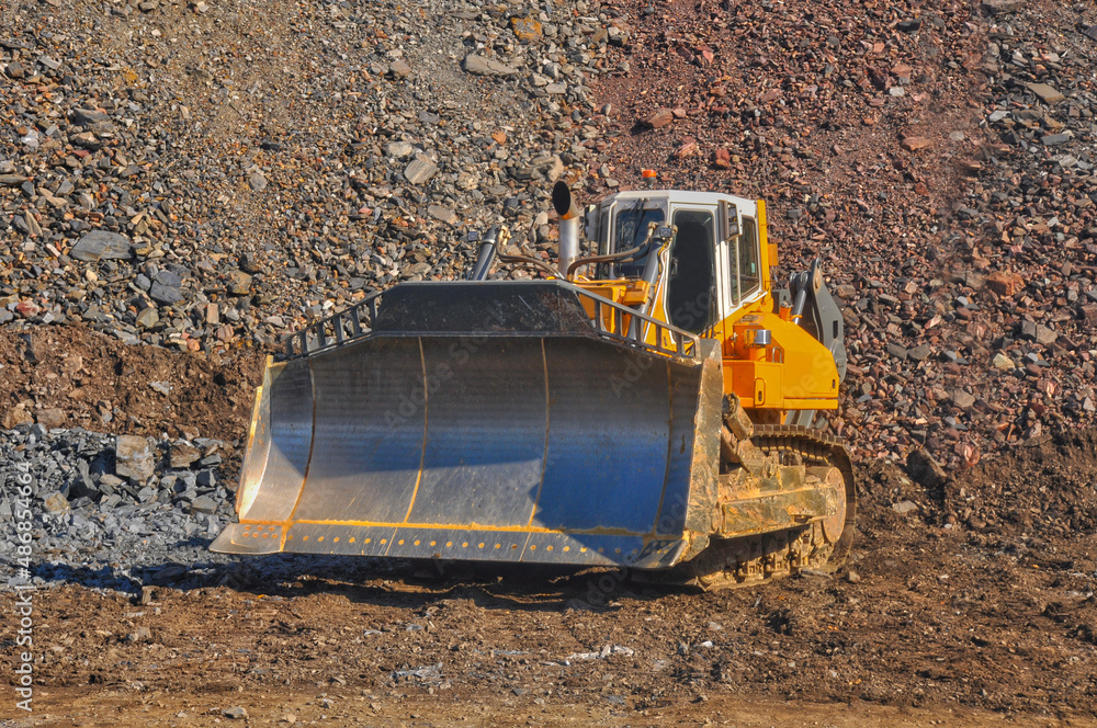 Bulldozer working in an iron ore quarry. Bulldozer clears the road from ...