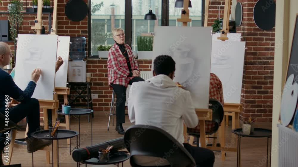 Elder teacher talking about drawing skills at art class lesson ...