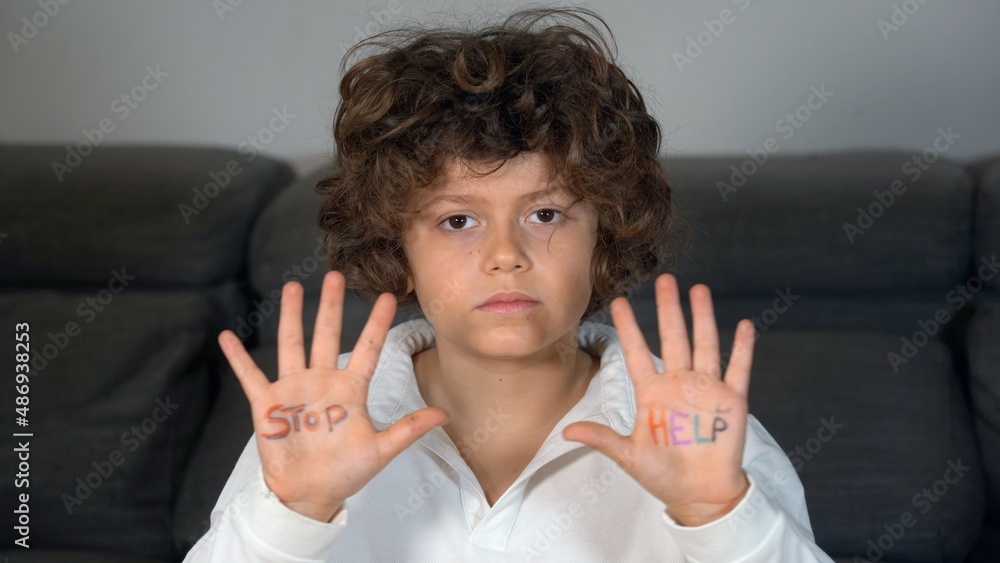 7 year old little boy alone with stop and help written on his hands ...