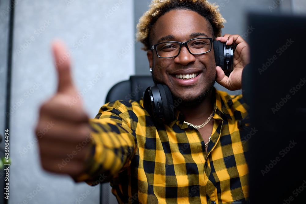 Smiling African-American gamer with headphones liked the game and he ...