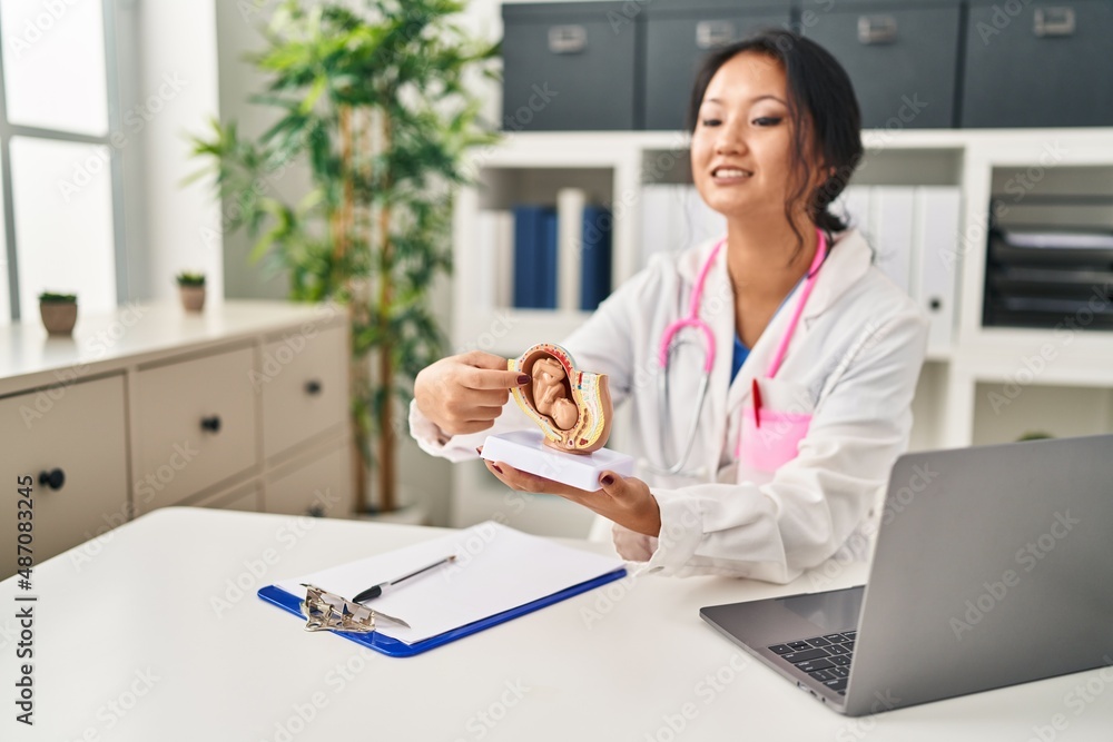 Young chinese woman wearing doctor uniform holding anatomical model of ...