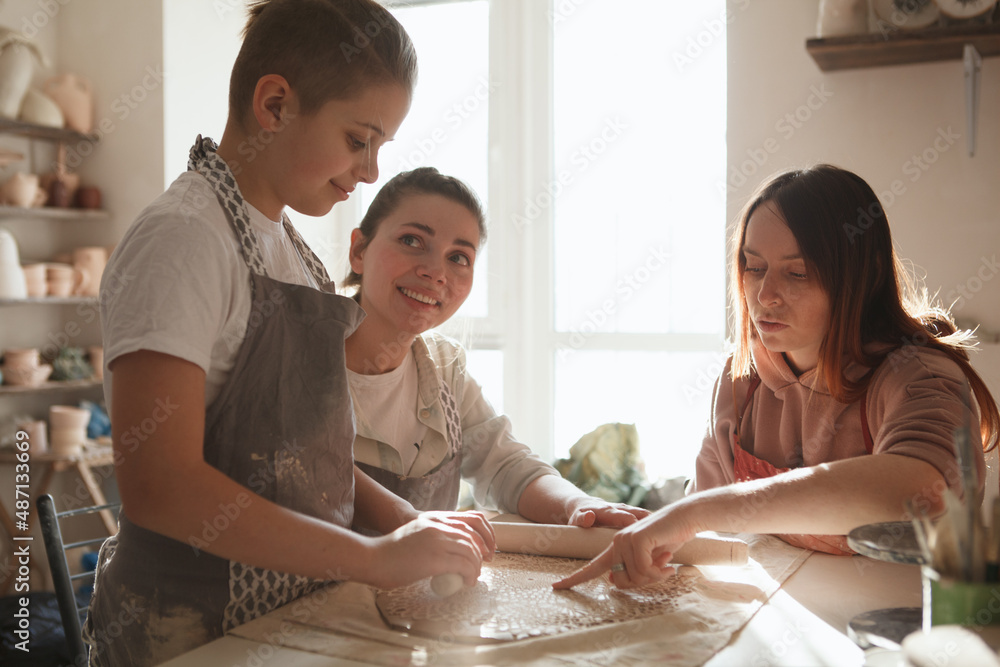Young boy making ceramics at pottery class with his mother and ...