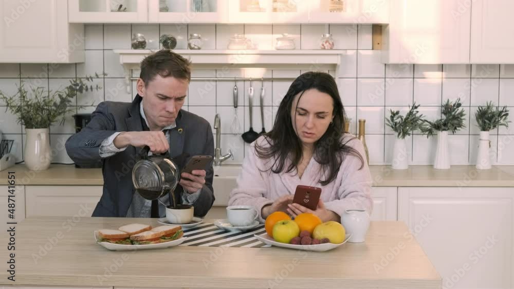 Couple Drinking Coffee while Using Smartphones in the Kitchen. Man in ...