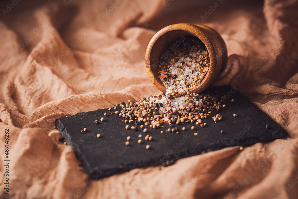 Coarse white salt is scattered from a mortar onto a black board. Adds ...