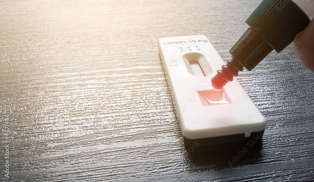 Close-up finger of Asian man dropping fluid on rapid antigen test kit ...