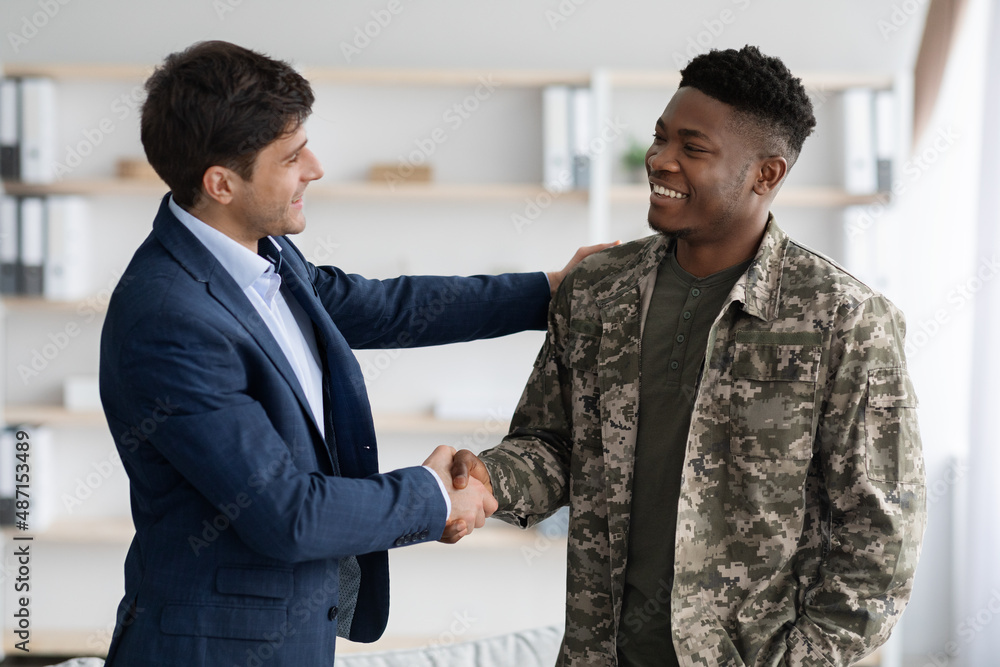 Cheerful guy in suit shaking black military man hand Stock Photo ...